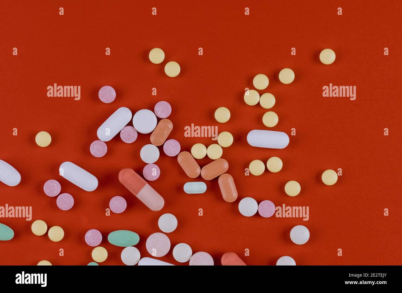 Medical capsules in red, yellow, white color pills on red background ...