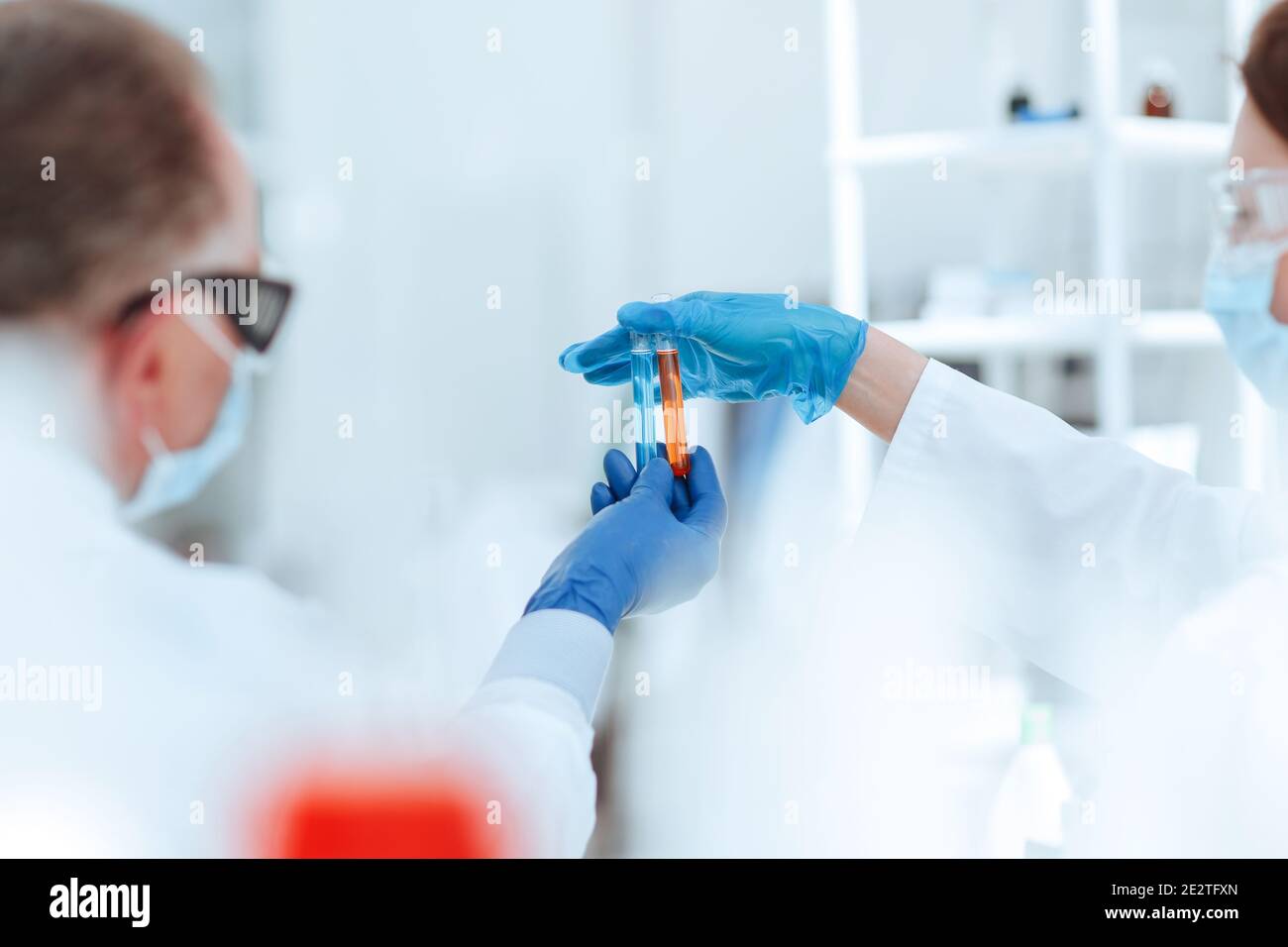 rear view . Microbiology scientists discussing the liquid in test tubes ...