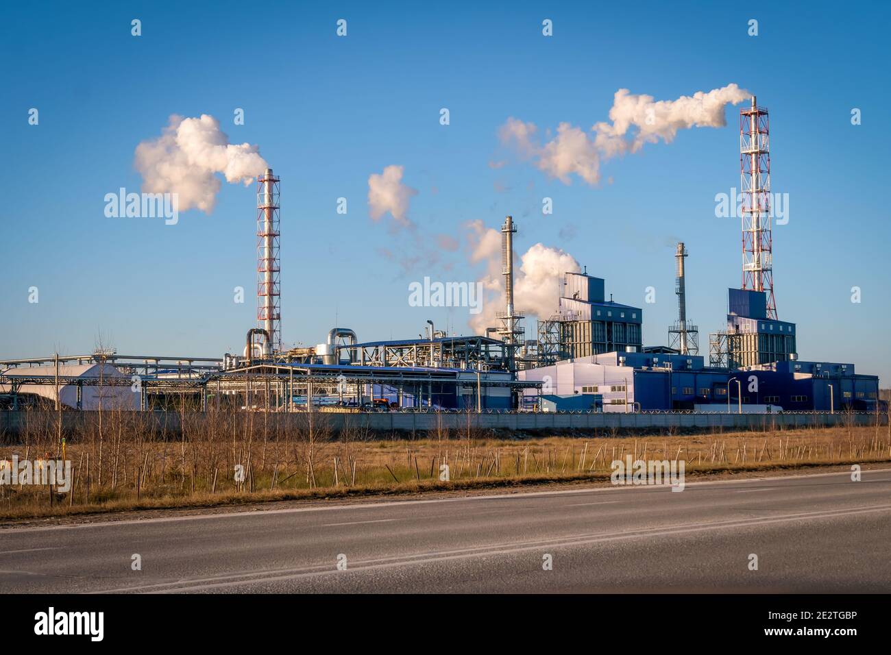 Pipes with huge clouds of smoke at the factory against the blue sky on ...