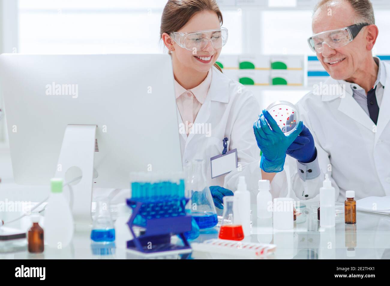 smiling scientists with a Petri dish sitting at a laboratory table ...