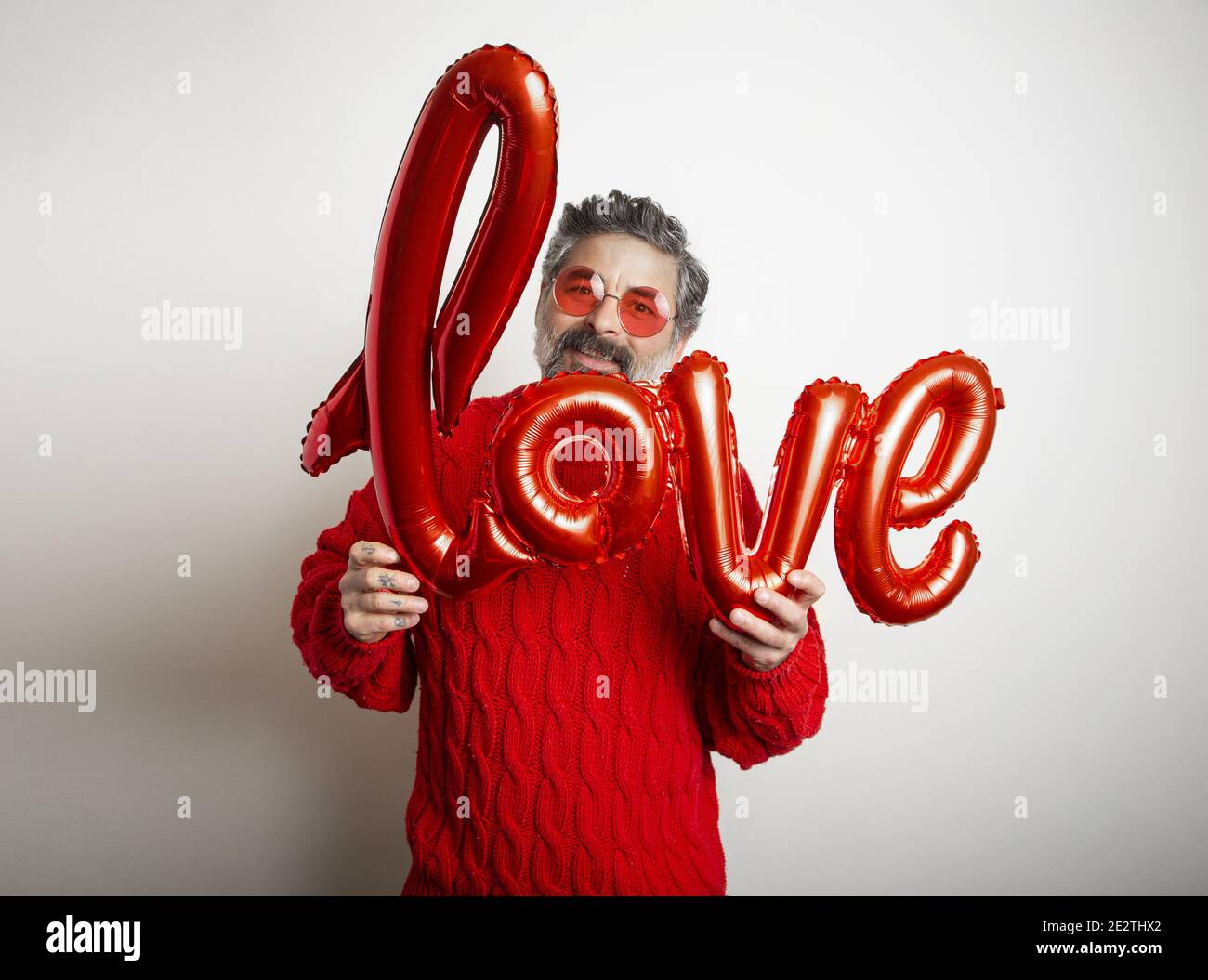 Friendly man with glasses holding a red balloon with the word love on ...