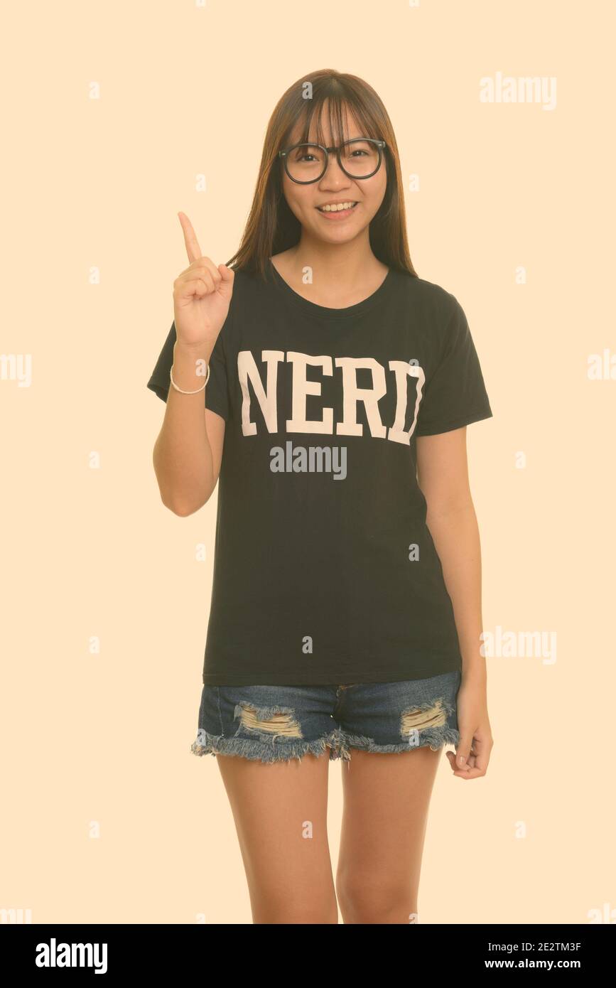 Young happy Asian nerd teenage girl smiling and pointing finger up ...
