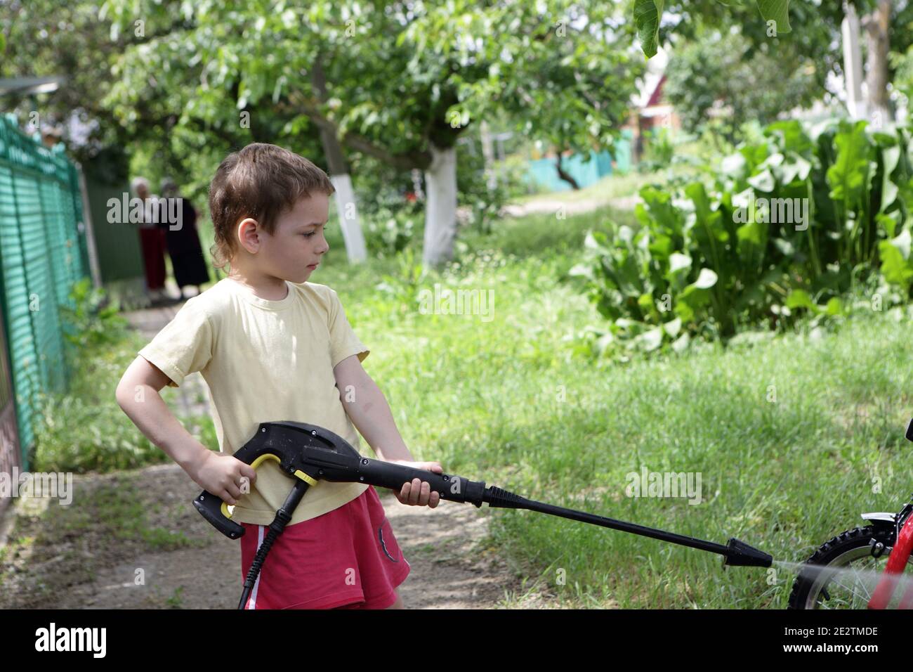 Child washing bike with high pressure washer at backyard Stock Photo ...