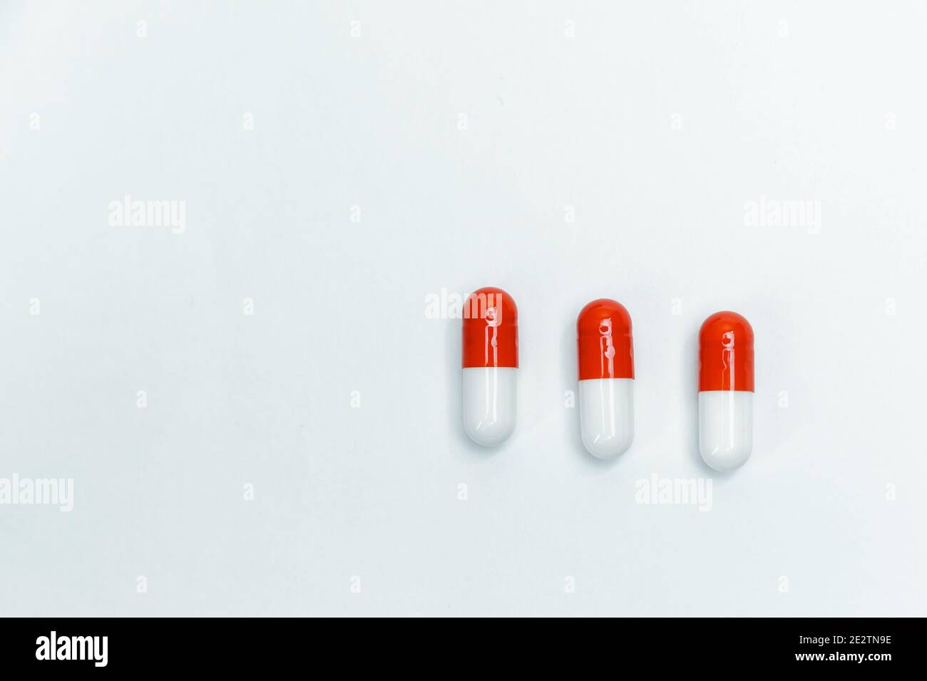 three red and white medical capsules on a white background Stock Photo ...