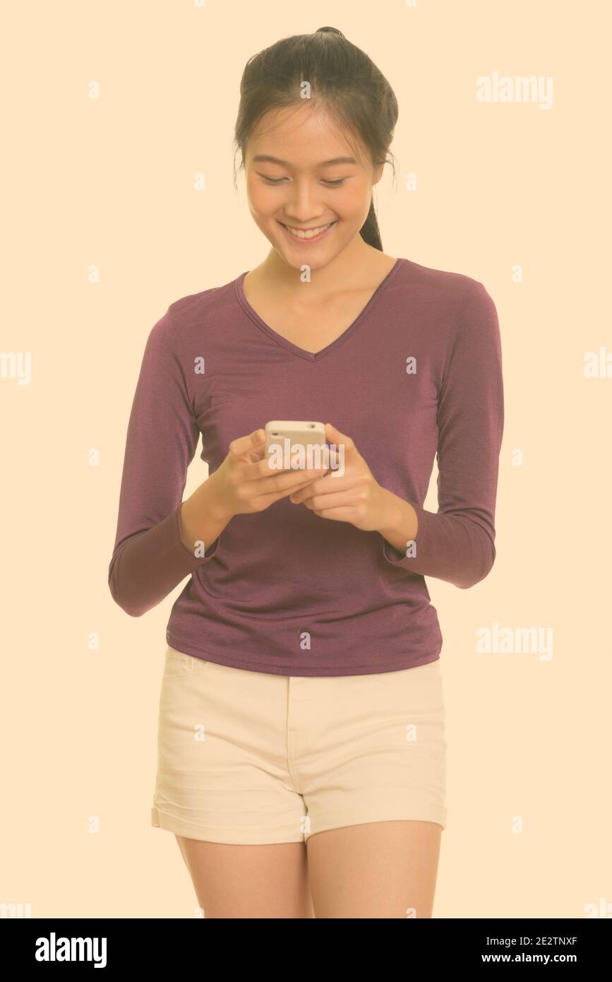 Young happy Asian teenage girl smiling and using mobile phone Stock ...