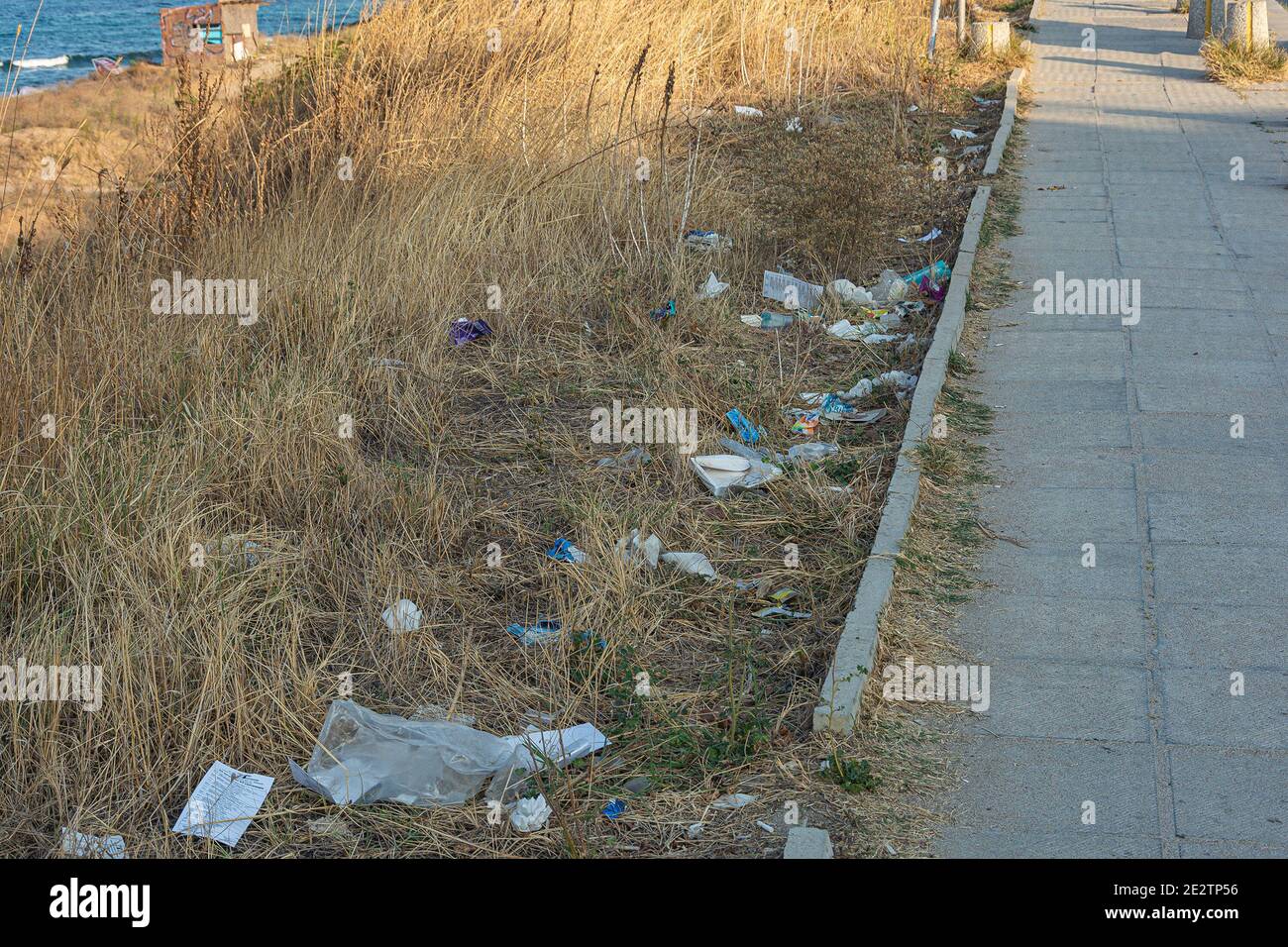 Garbage on the grass along the pedestrian sidewalk. Stock photo Stock ...
