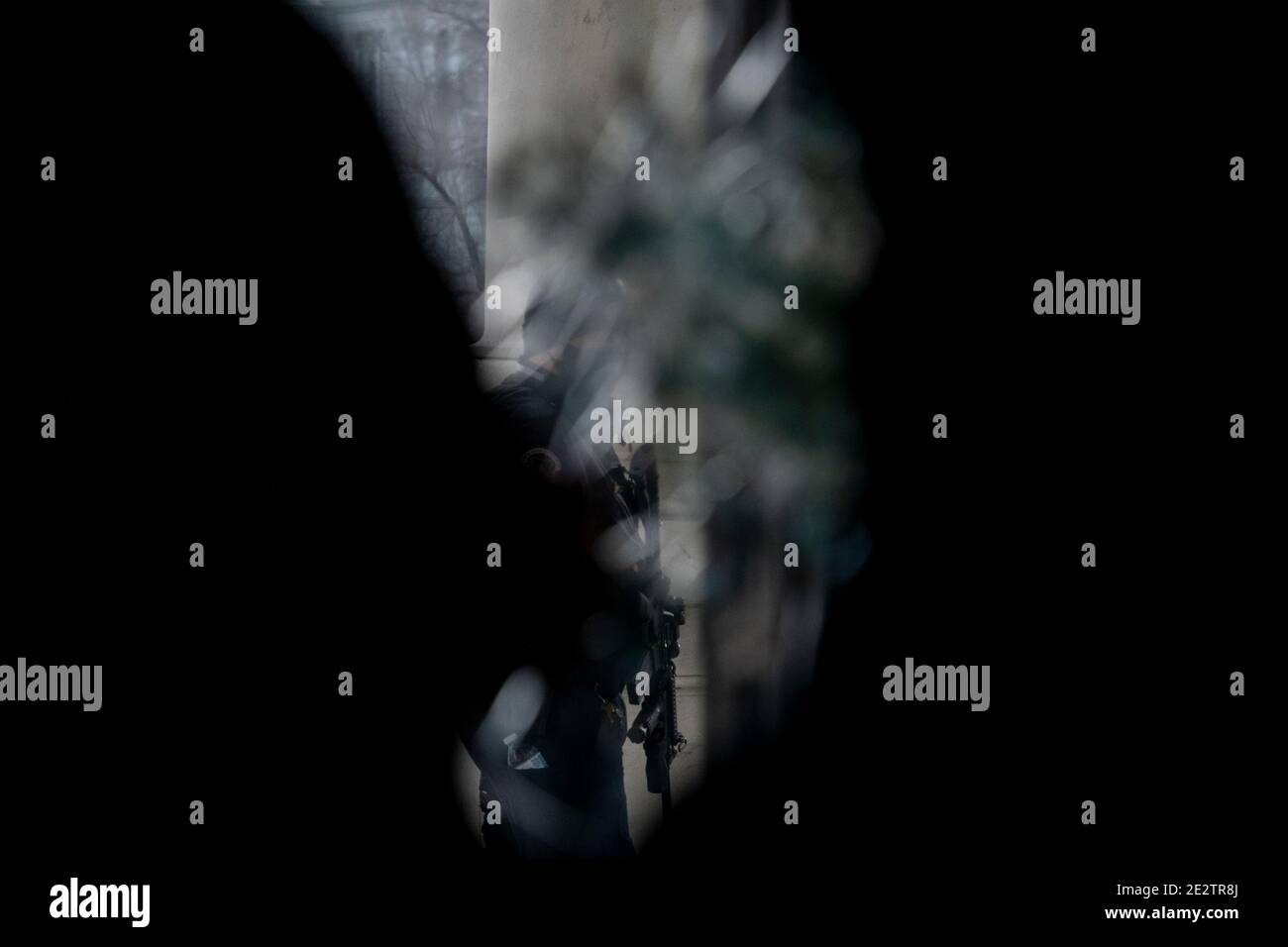 A Capitol police officer is seen through the scattered glass window of ...