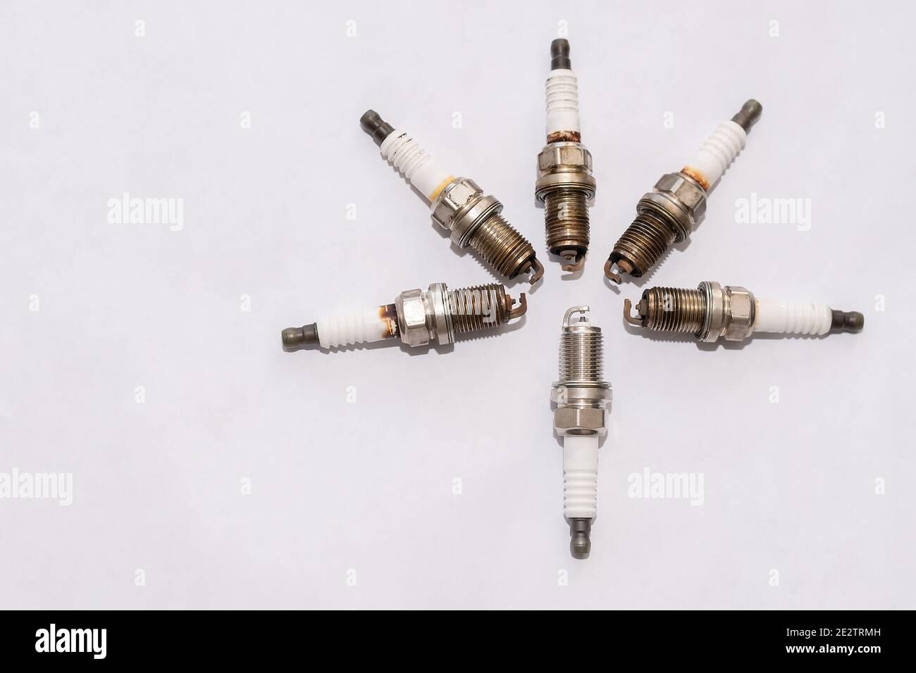 a set of old worn out petrol car spark plugs lie next to one new one on ...