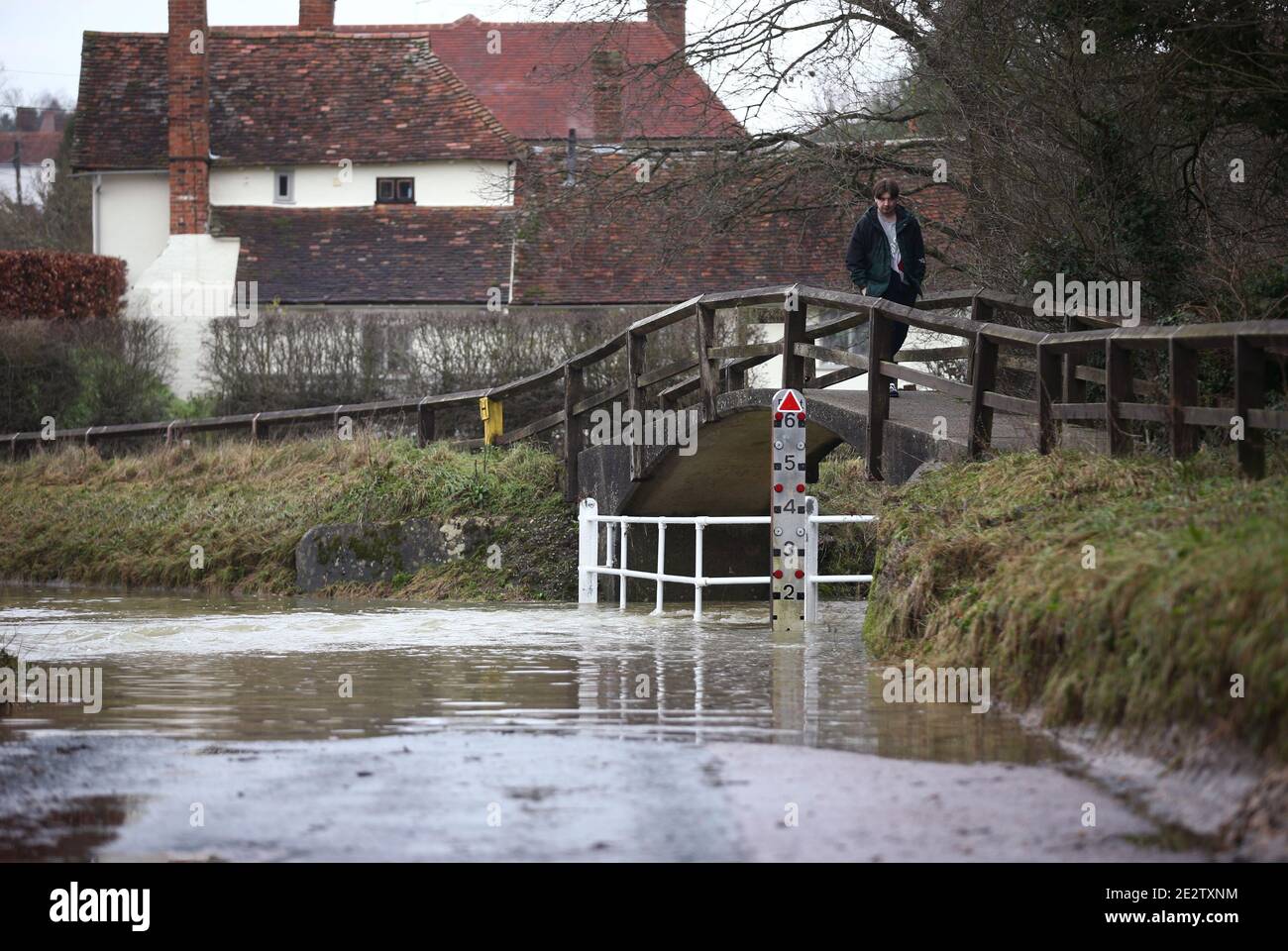 A man crosses a bridge over a flooded road in the village of Great ...