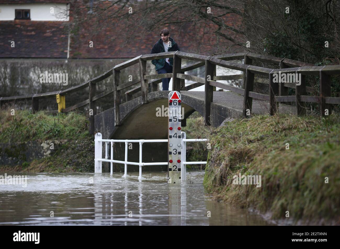 A man crosses a bridge over a flooded road in the village of Great ...