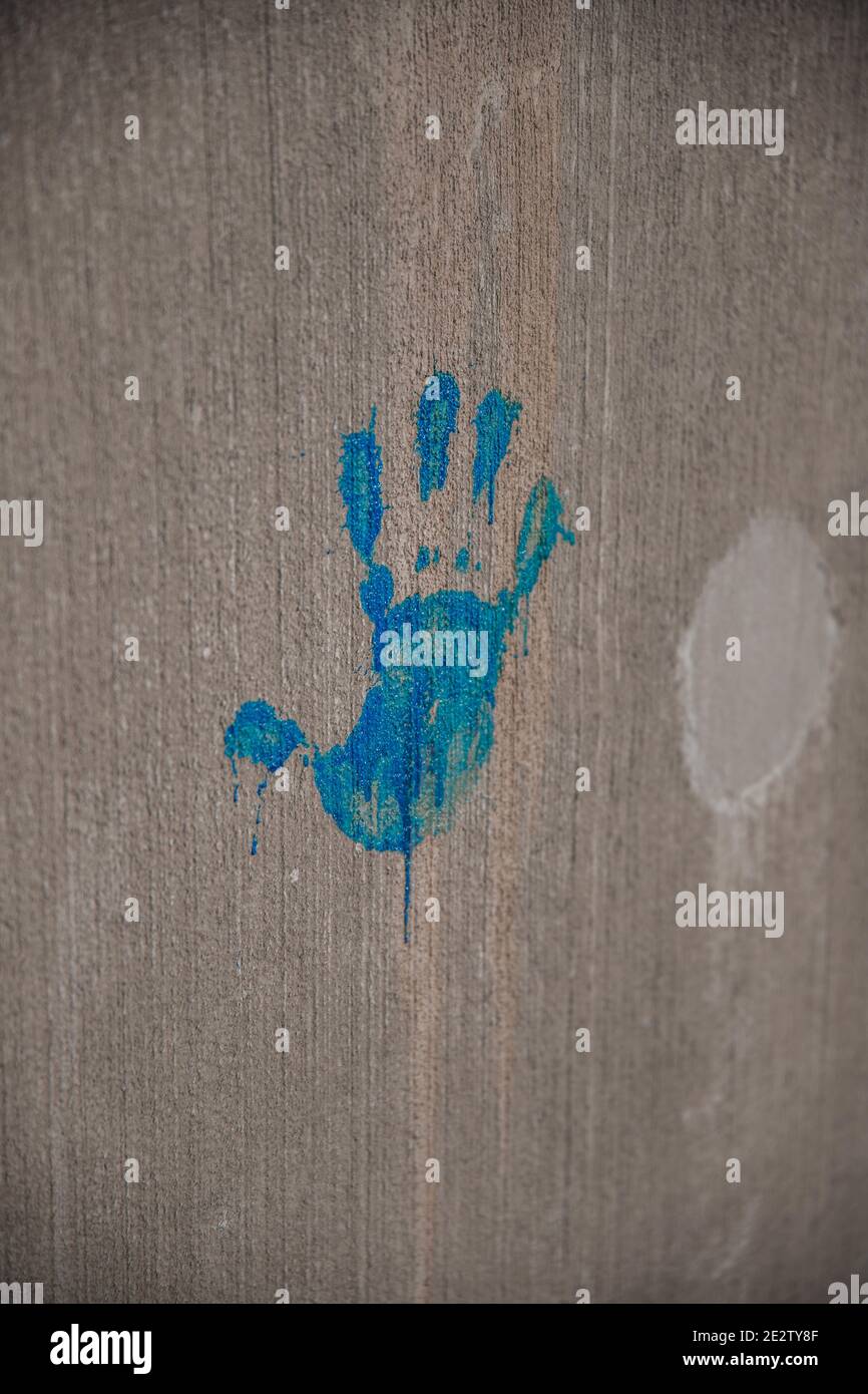 Vertical shot of a blue handprint of a child on the wall of a building ...