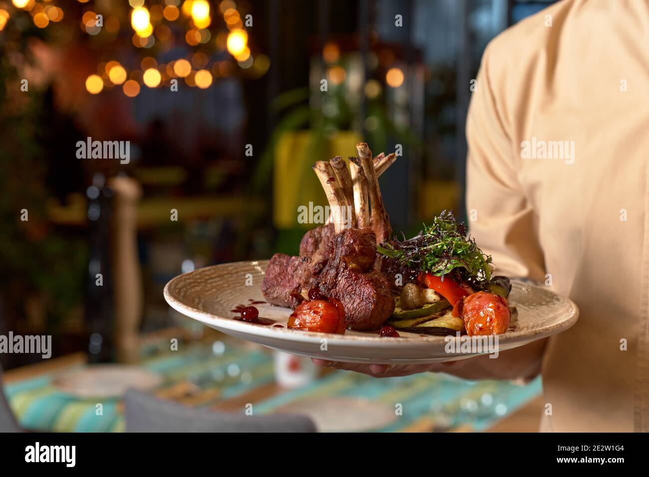 Hands holding cooked Tomahawk long bone ribeye steak on a plate in ...
