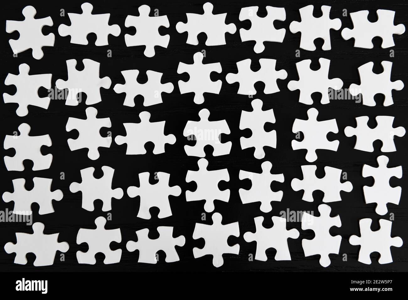 Grid rows of white jigsaw puzzle pieces on a black table Stock Photo ...