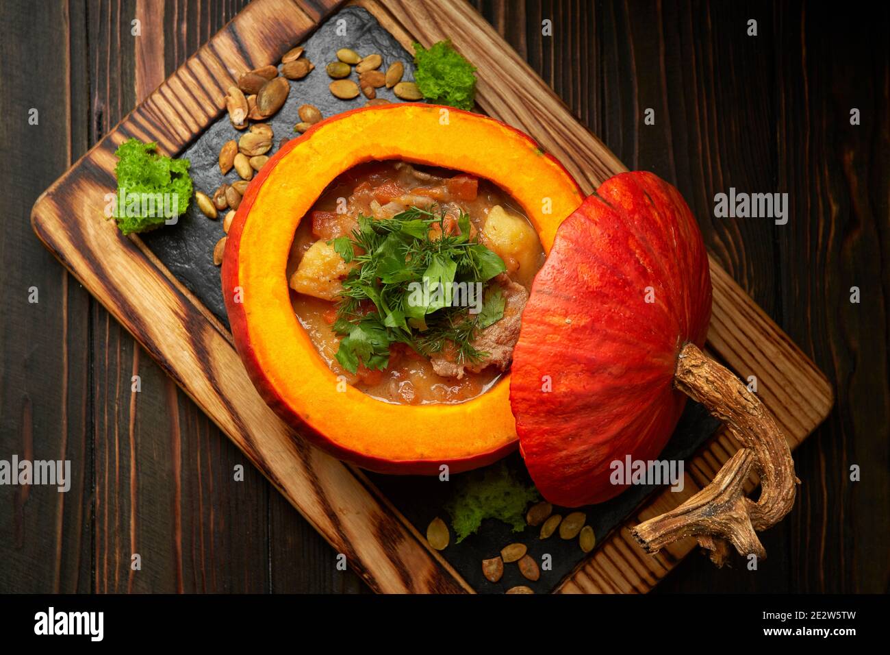 Roast with meat and potatoes in a pumpkin, on a wooden background with ...