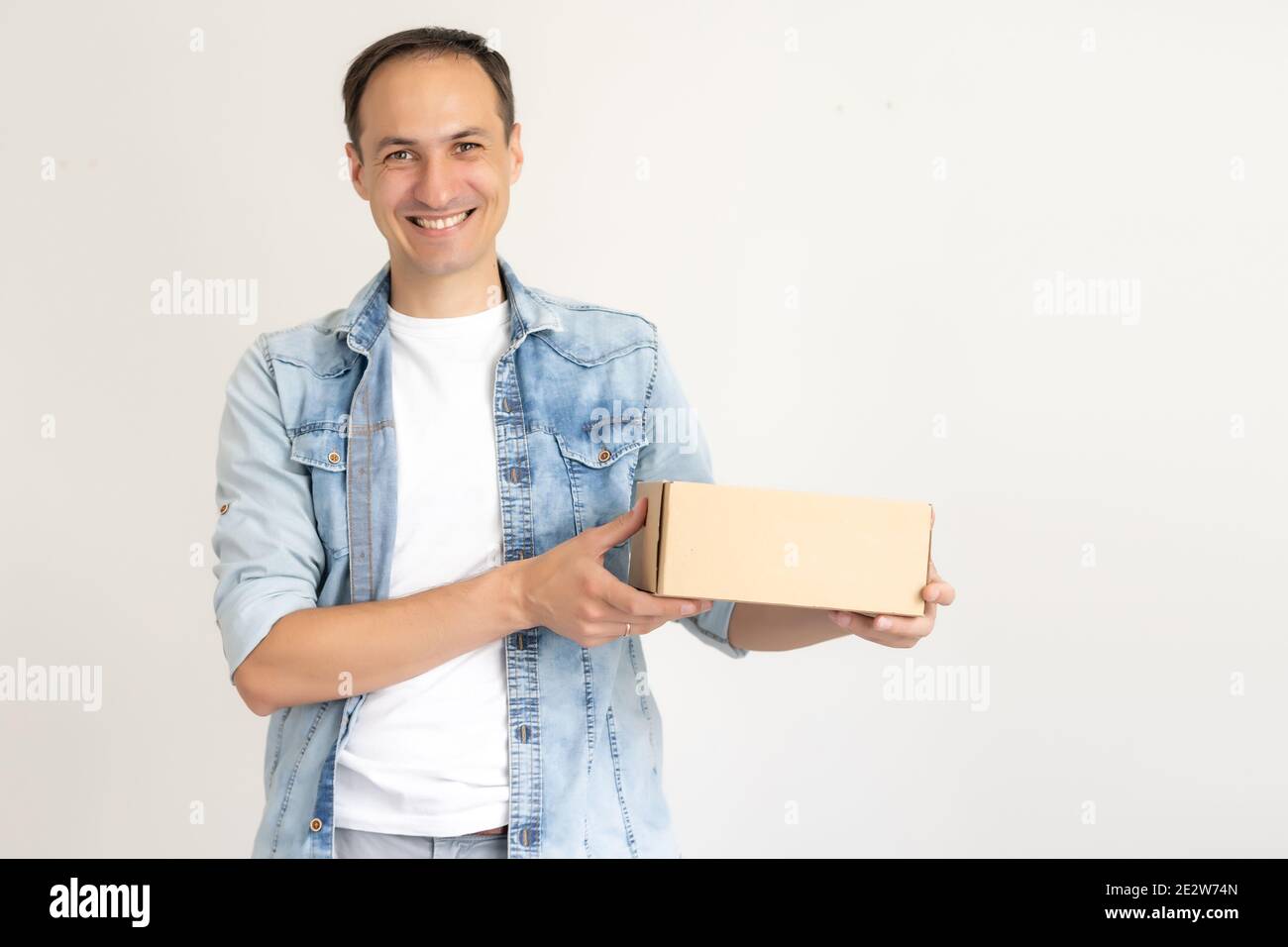 smiling delivery man holding a big parcel isolated on white Stock Photo ...