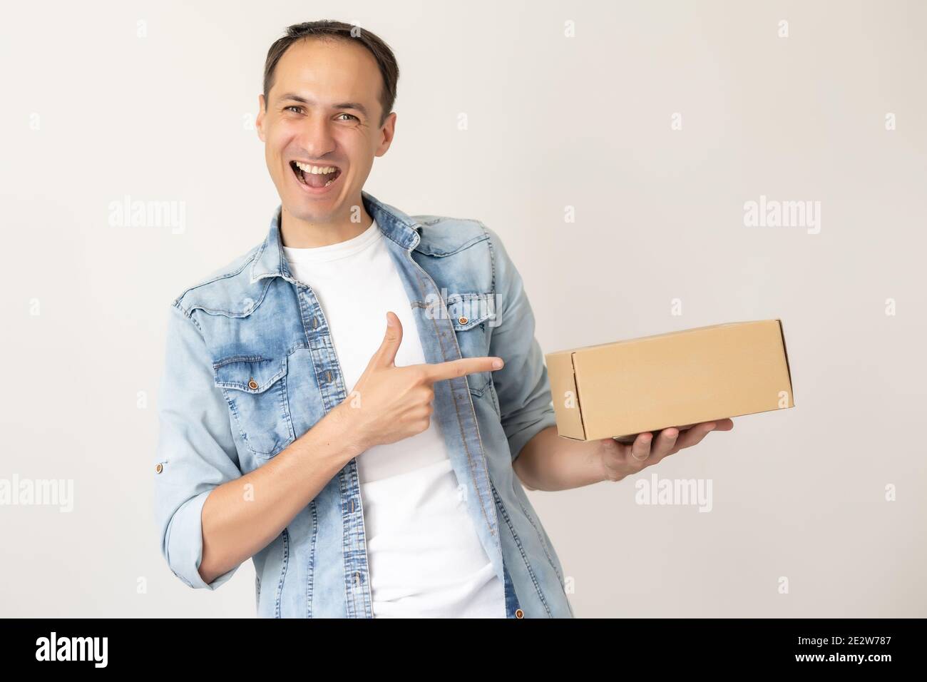 Smiling delivery man giving cardbox on white background Stock Photo - Alamy