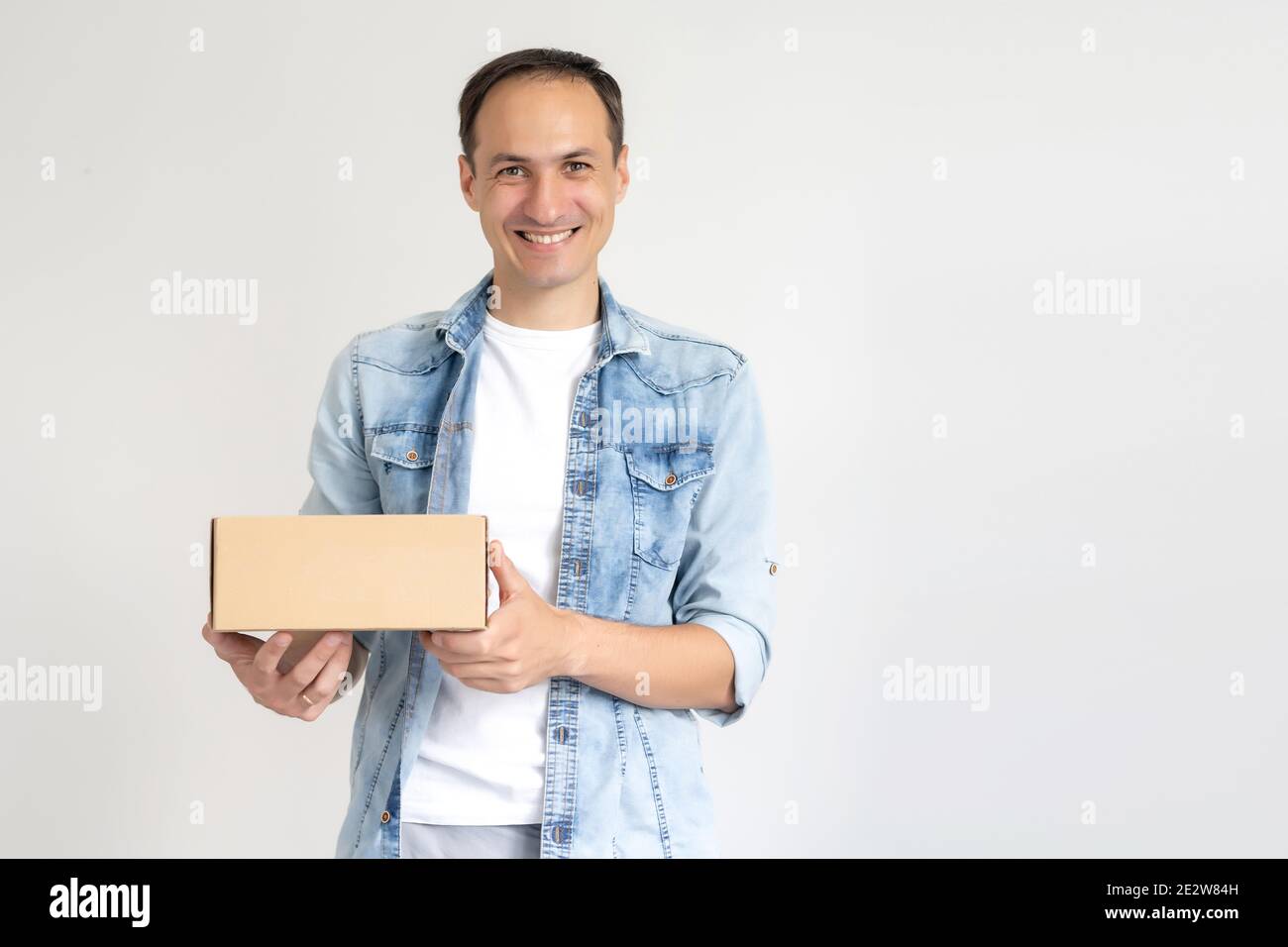 smiling delivery man holding a big parcel isolated on white Stock Photo ...