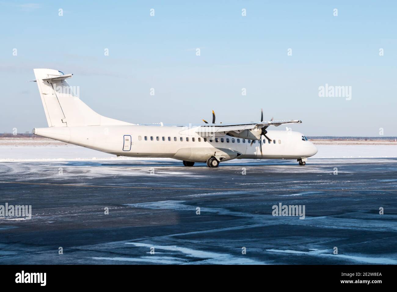 White passenger turboprop aircraft on the airport apron in cold winter ...