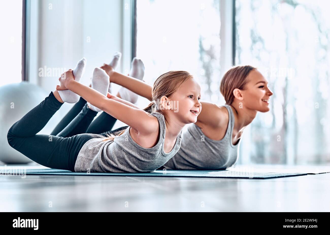Side view of cute blonde little girl repeats bow pose for her young ...