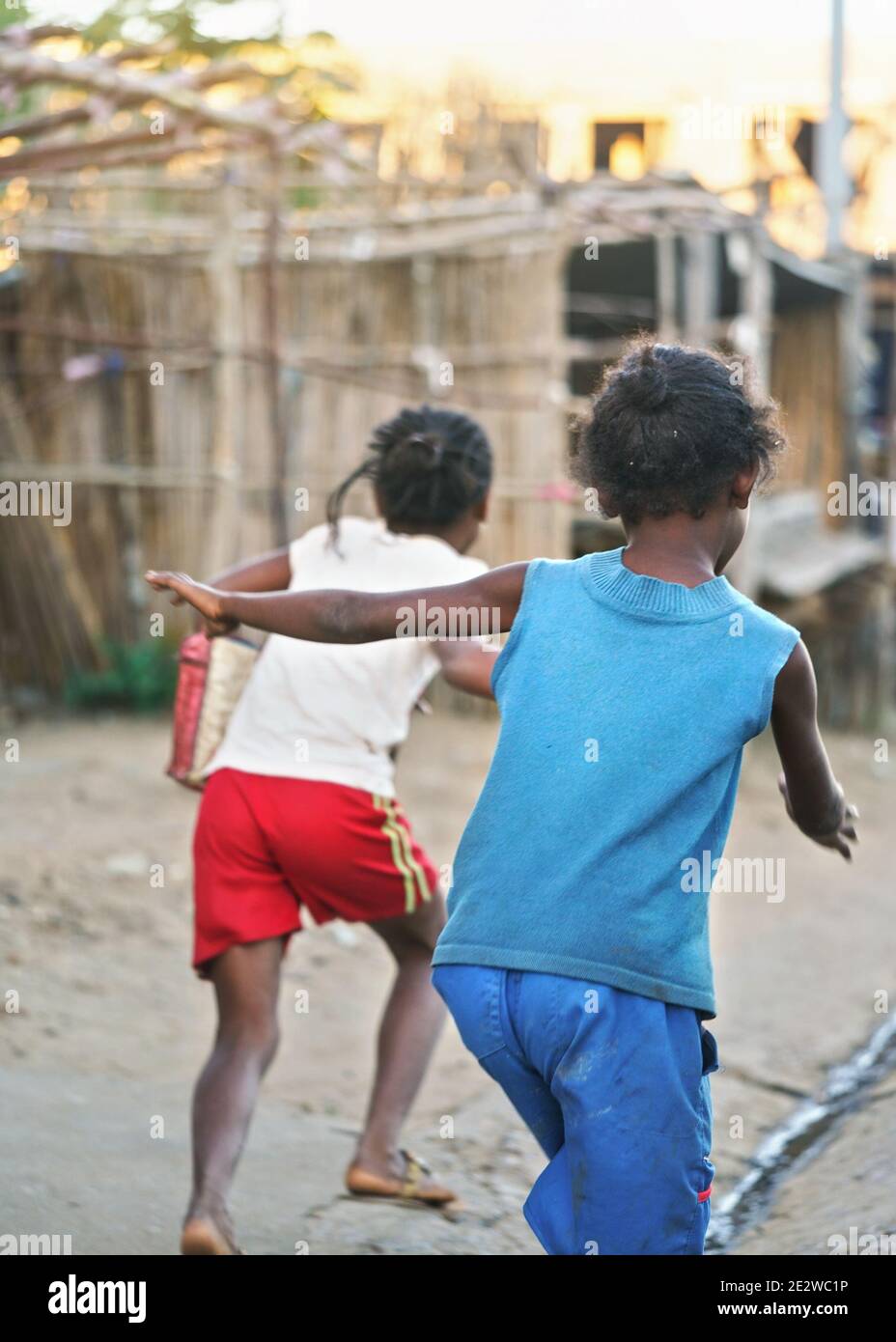 Two African kids playing, running on dusty road, view from behind Stock ...