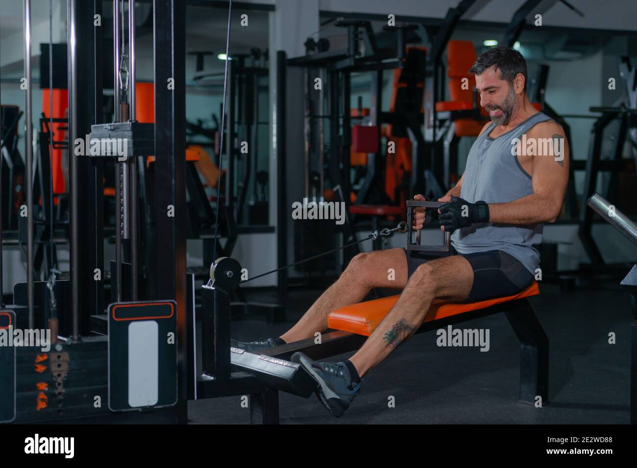 Fitness training in sport gym of active male with beard sitting and ...