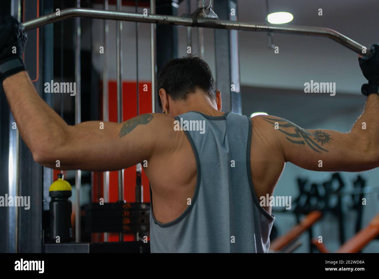 Strong 50 year old man exercising lat pushdown at the cable machine in ...