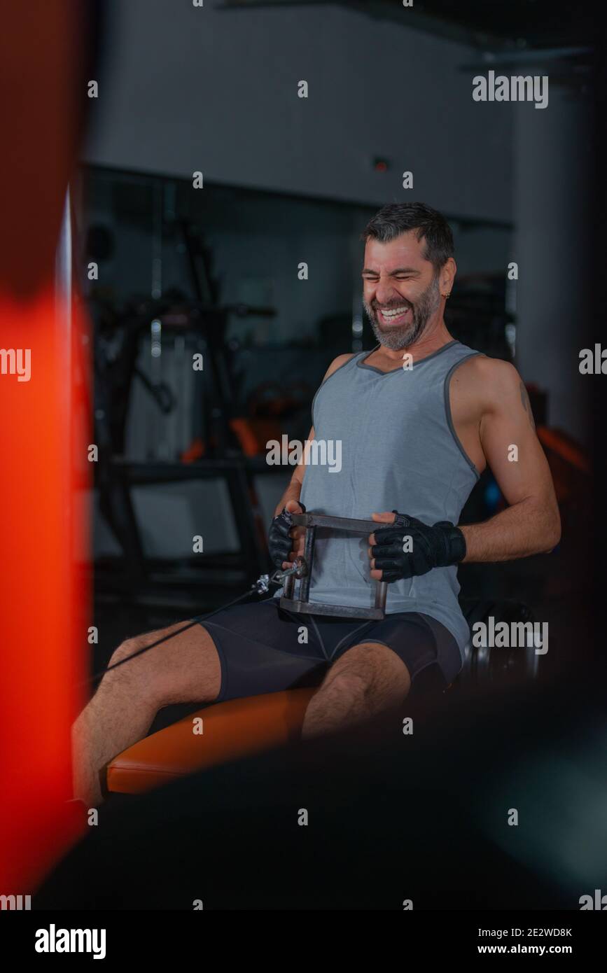 Fitness training in sport gym of active male with beard sitting and ...