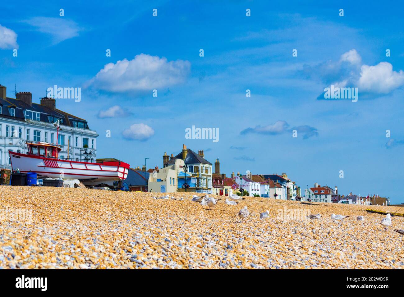 Traditional fishing boat and seagulls relaxing on a pebble beach ...