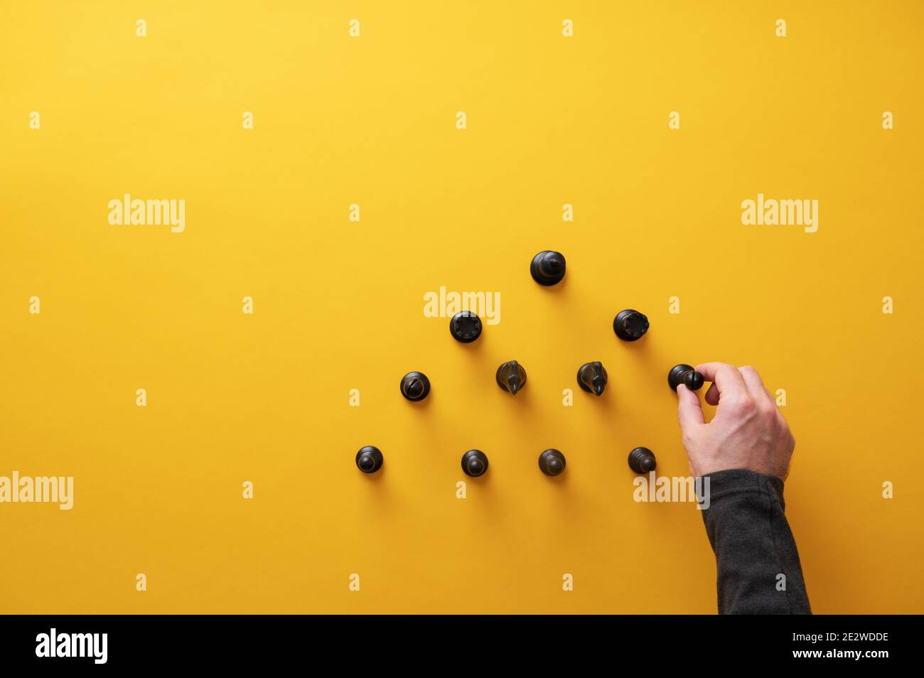 Top view of male hand positioning chess pieces in pyramid structure in ...