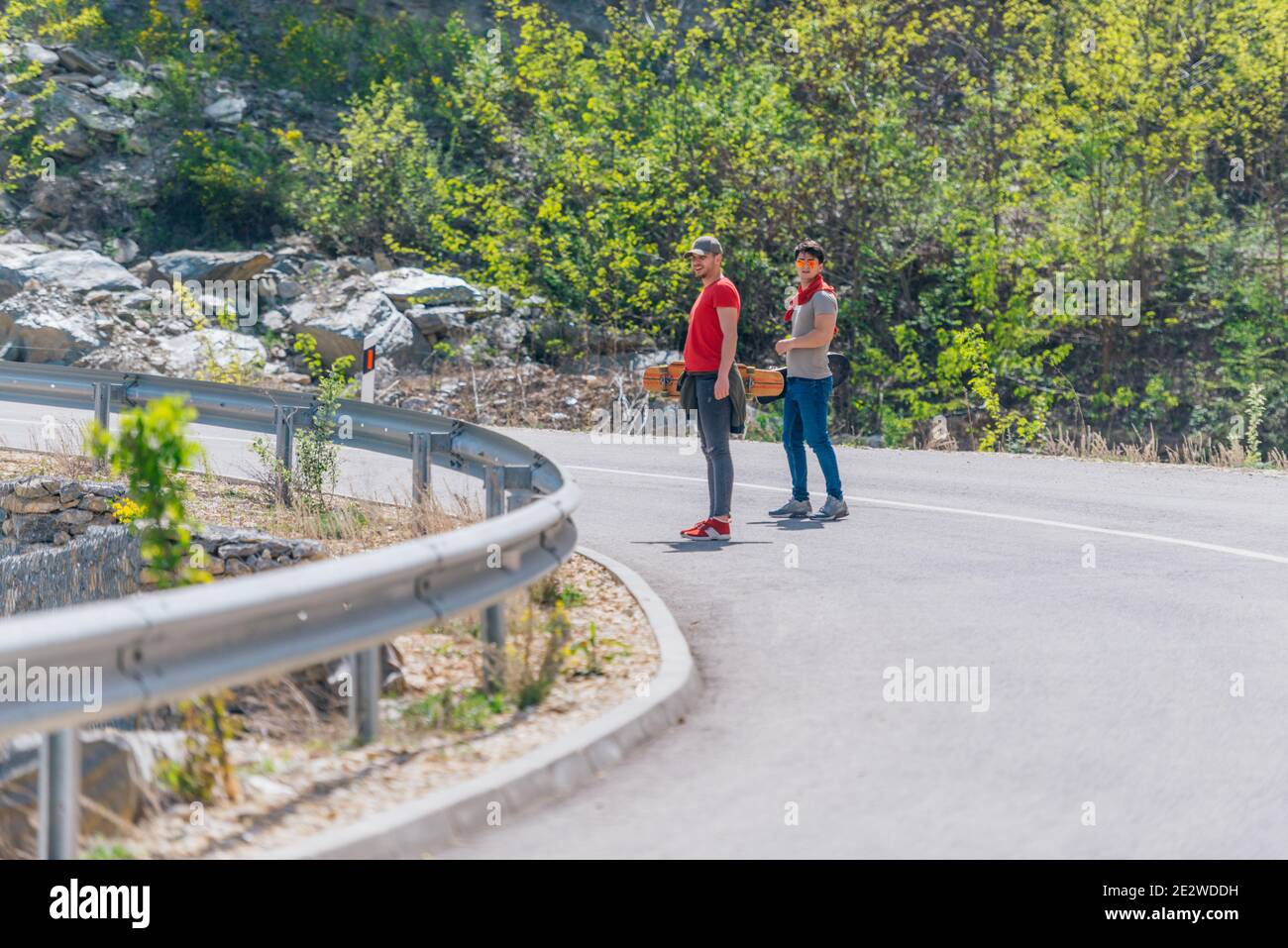 Two male longboarders carrying their longboards in their hands while ...