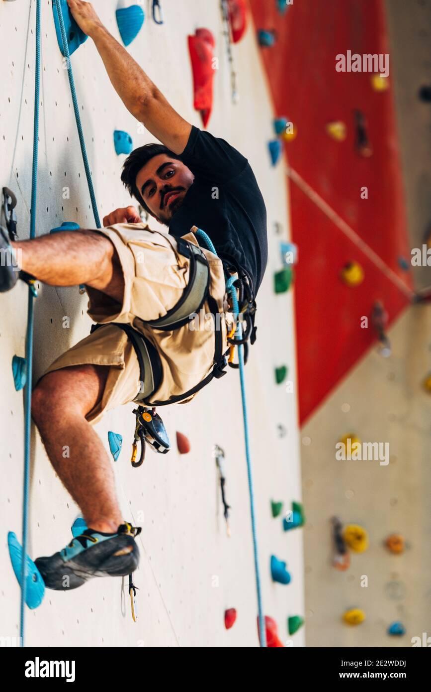 Young climber guy climbing on practical rock in climbing center ...