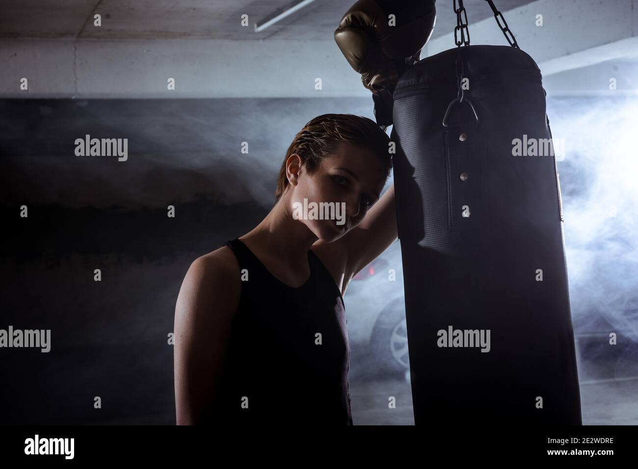 Silhouette picture of female boxer leaning her head on the punching ...