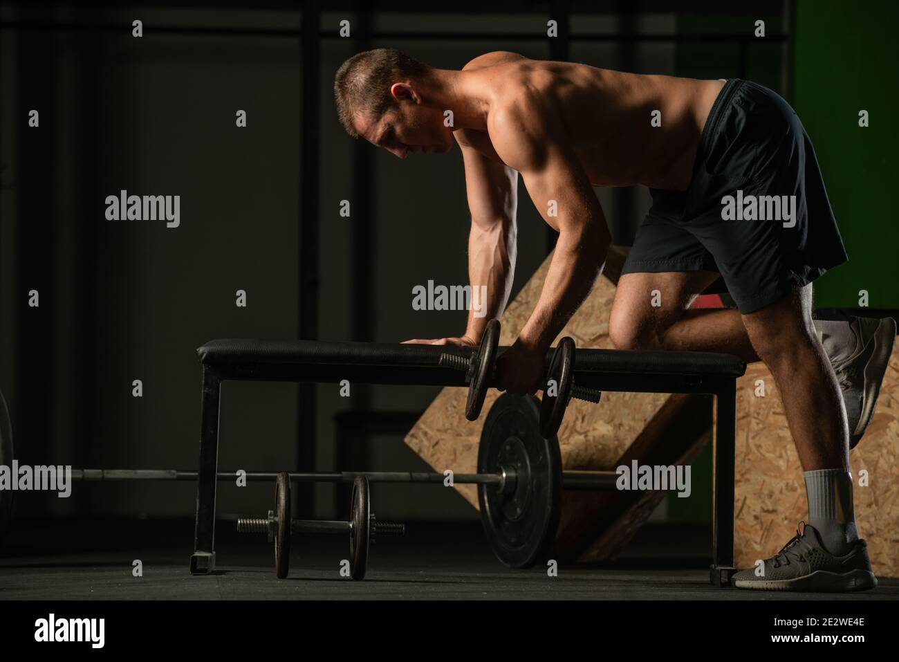 Good looking young man doing triceps dumbbell kickback exercises with ...
