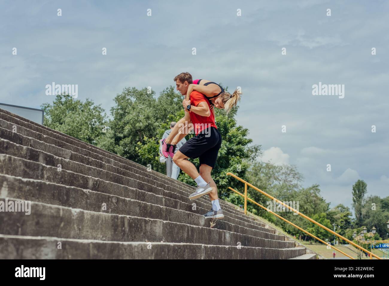 Male athlete carrying his female workout partner on his shoulders while ...