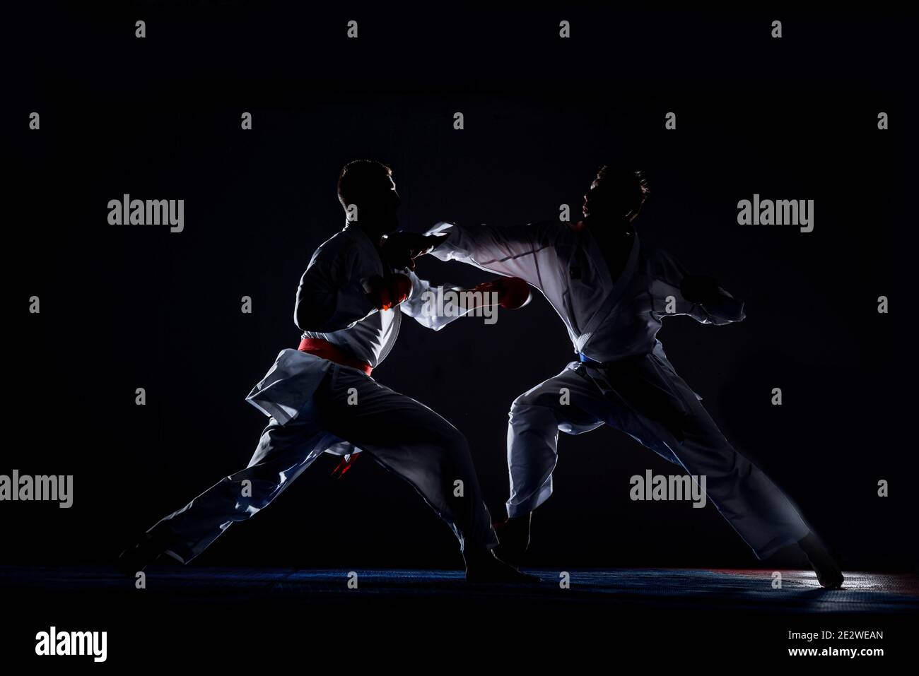 Young sporty man in white kimono training karate kata moves in gym ...