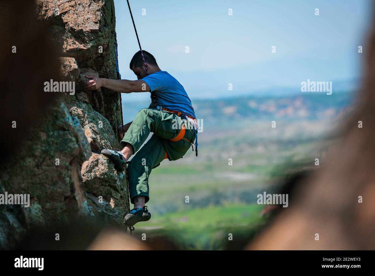 Portrait of strong sporty fit male is climbing the big natural boulder ...