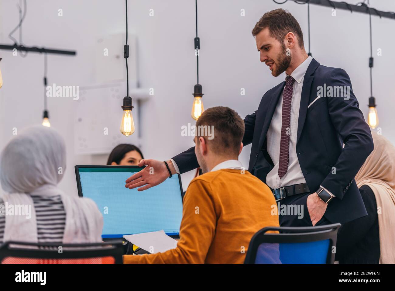 The manager is checking on his colleagues and is showing them what can ...