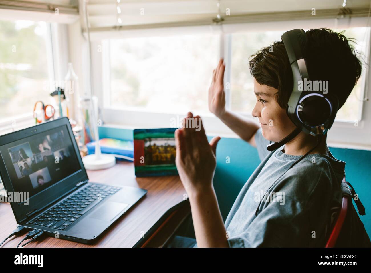 Boy Waves To Teacher And Classmates During A Zoom Class Stock Photo - Alamy