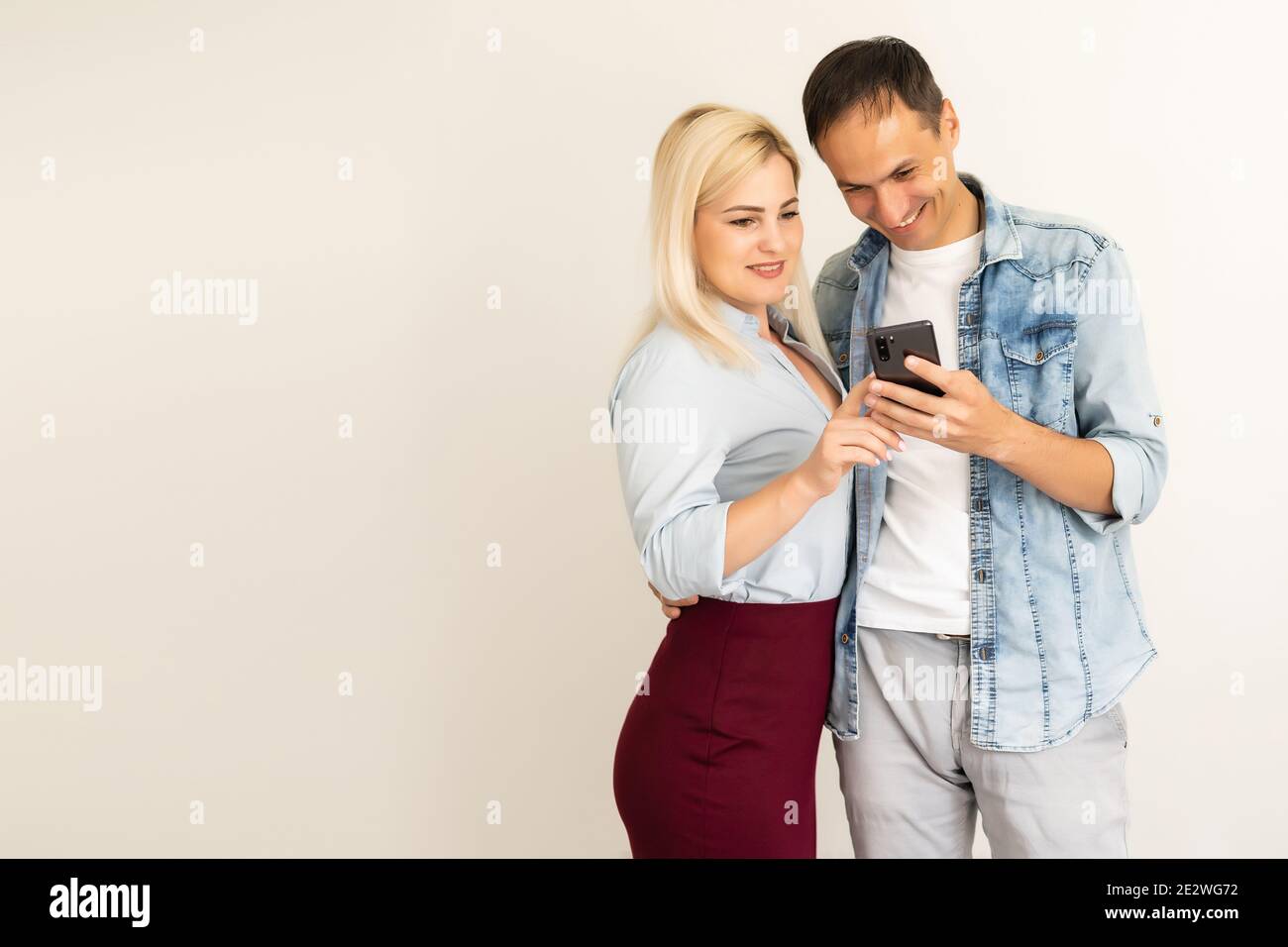 Happy couple using smartphone together Stock Photo - Alamy