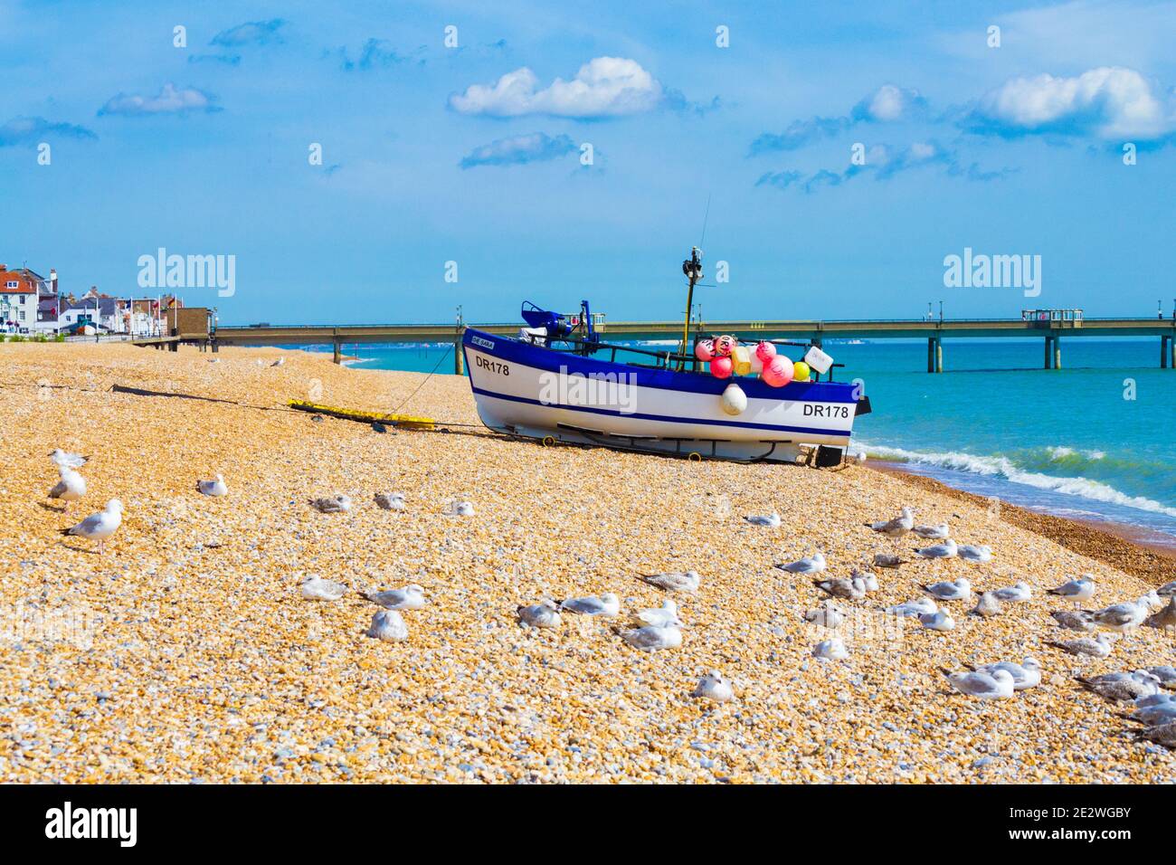 Traditional fishing boat and seagulls relaxing on a pebble beach ...