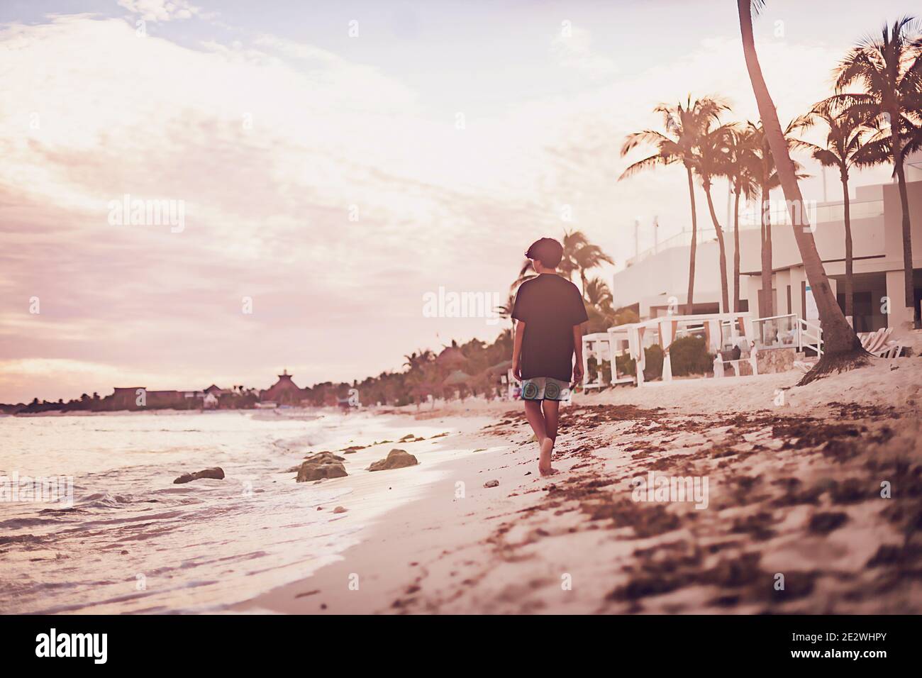 Pre teen boy walking on a tropical beach at sunset Stock Photo - Alamy
