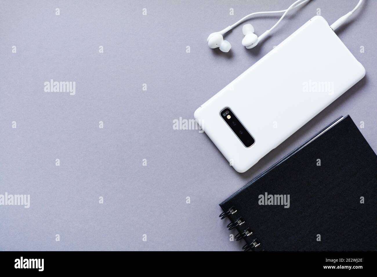 Modern White headphones, a notepad for notes and a mobile phone on a ...