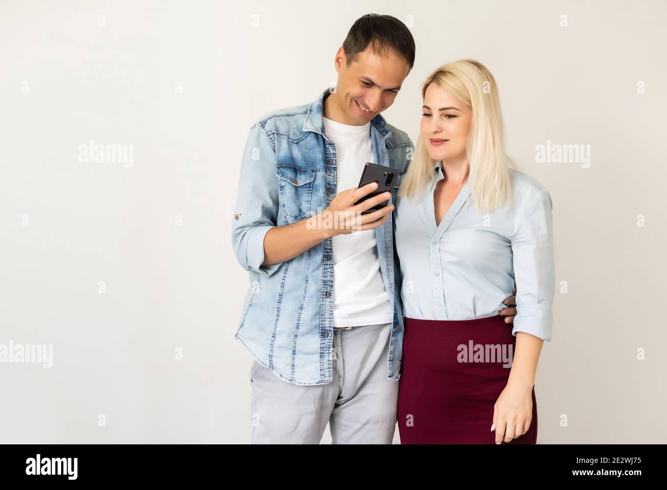 Happy couple using smartphone together Stock Photo - Alamy