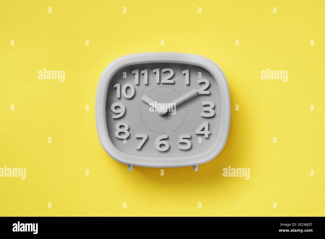 Grey retro alarm clock on yellow background with copy space. Time ...
