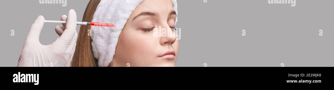 Cheek injection at spa salon. Doctor hands. Pretty female patient ...