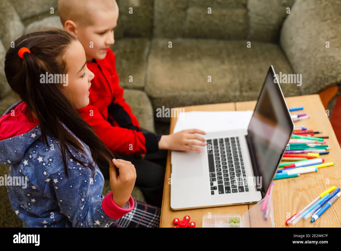 Two beautiful cute happy smiling children, a boy and a girl, use laptop ...