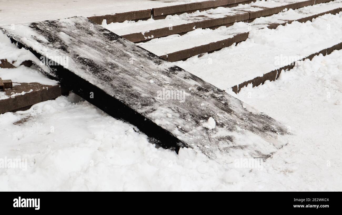 Snow covered slippery concrete stairs and wooden ramp. First snow on ...