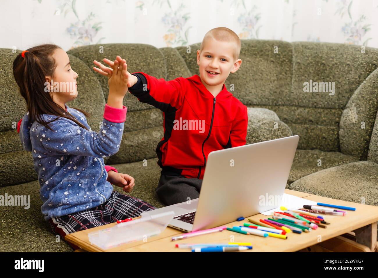 Two beautiful cute happy smiling children, a boy and a girl, use laptop ...