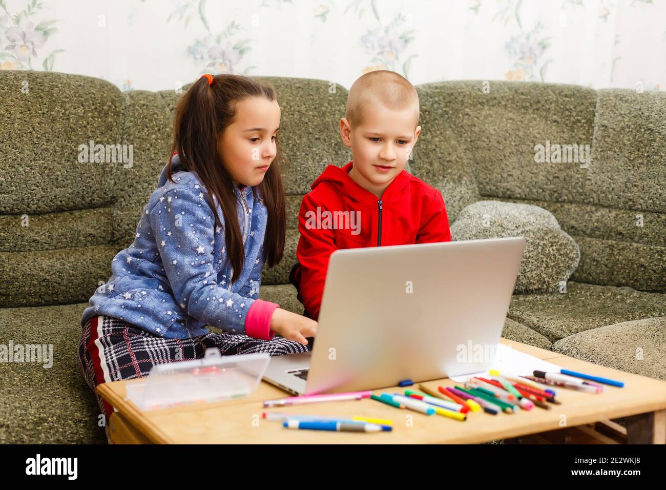 Two beautiful cute happy smiling children, a boy and a girl, use laptop ...
