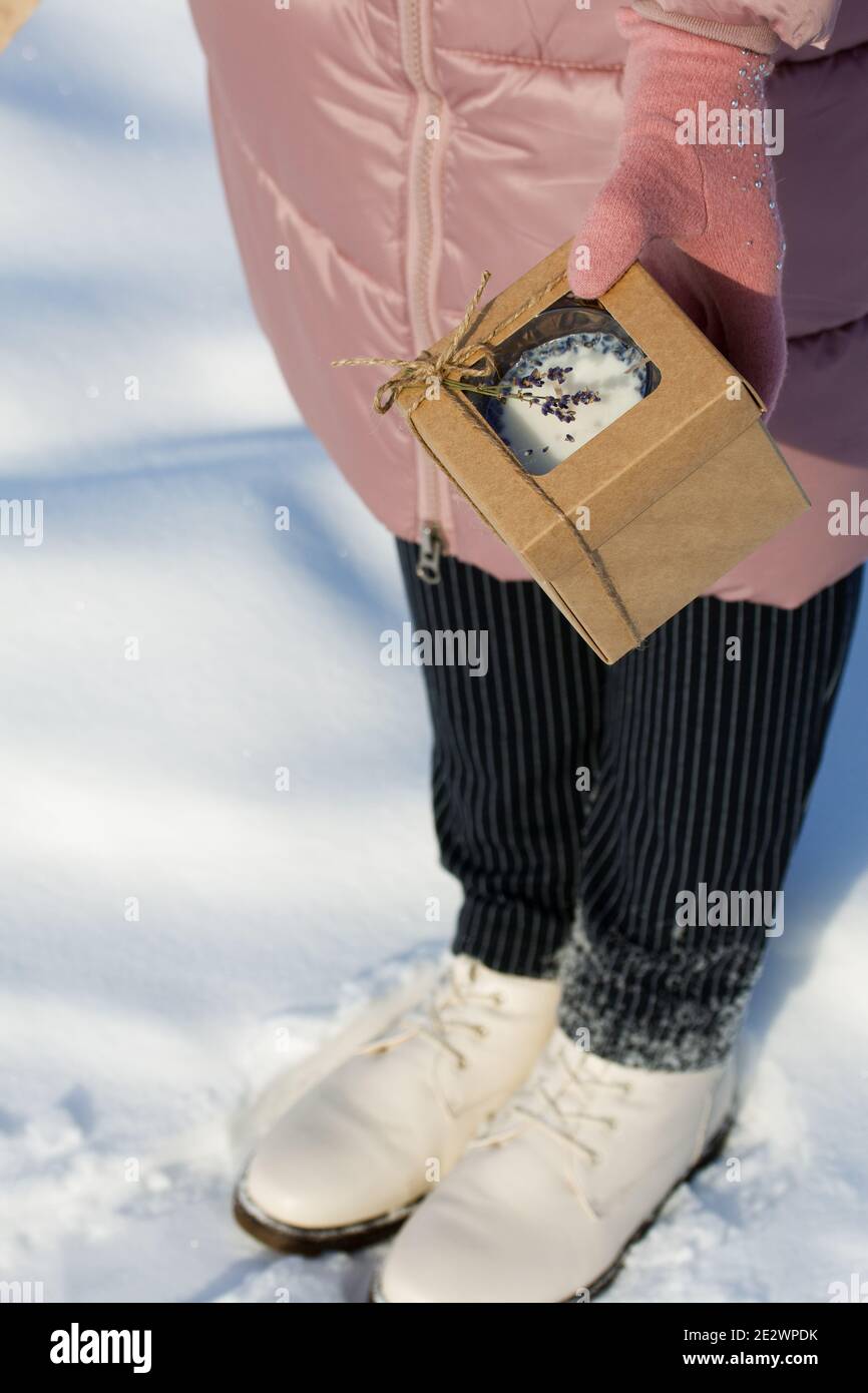 Girl in winter clothes. He is holding a cardboard box with candles ...